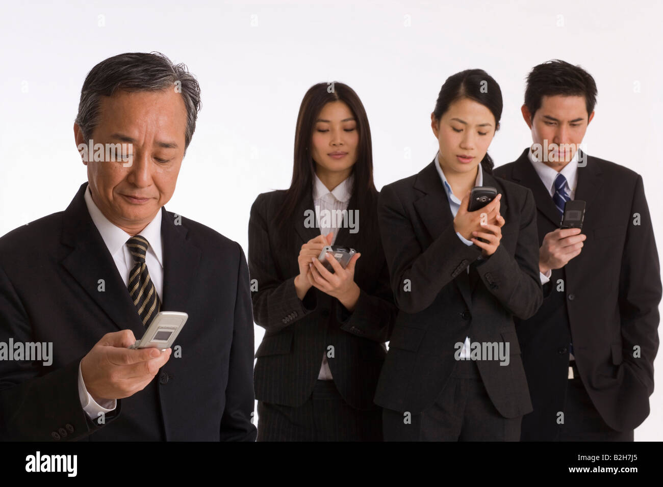 Four business executives using their mobile phones Stock Photo - Alamy