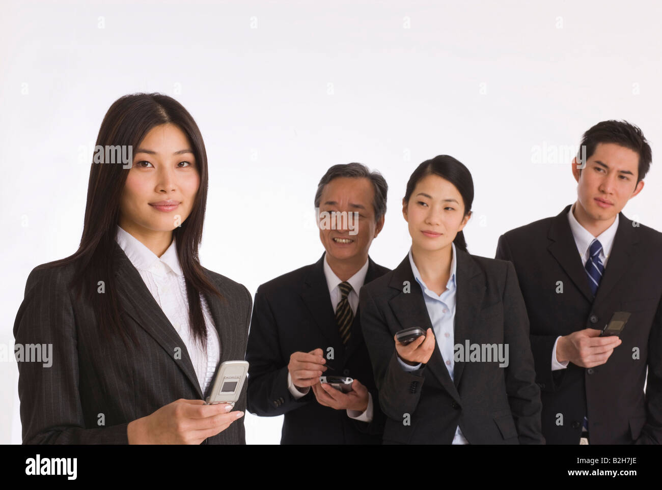 Four business executives using their mobile phones Stock Photo - Alamy