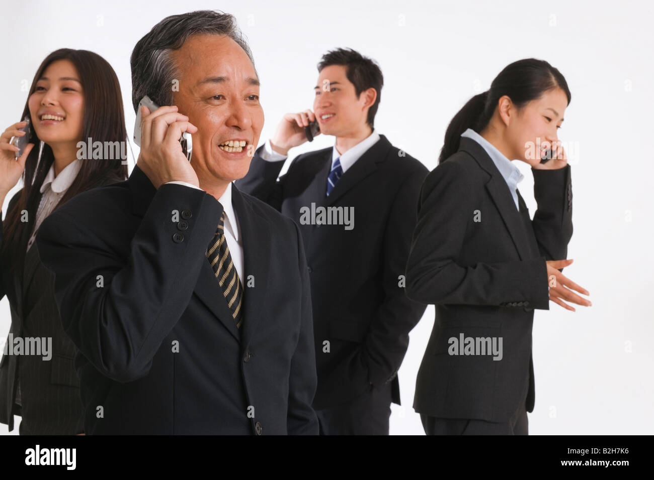 Four business executives using their mobile phones Stock Photo - Alamy
