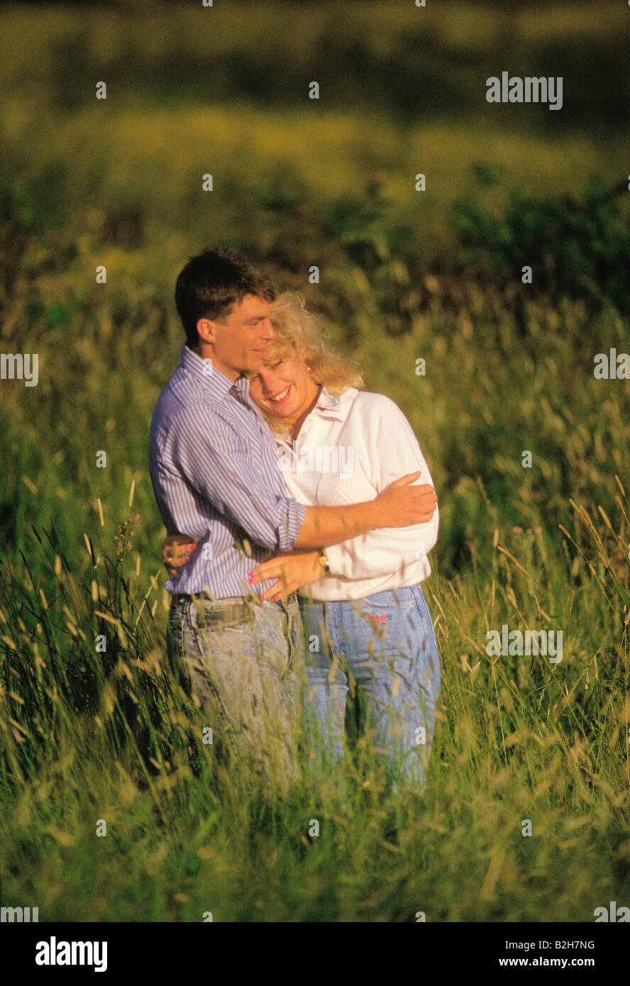 Young smiling couple hugging and standing in a field Stock Photo - Alamy