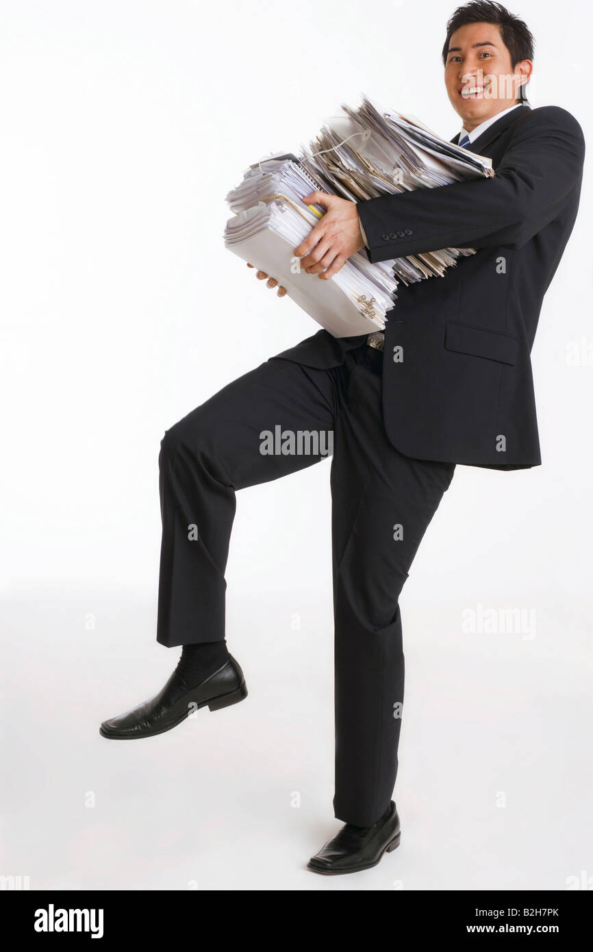 Businessman struggling to carry a stack of files Stock Photo - Alamy