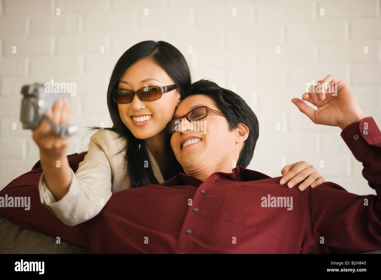 Young couple filming themselves with a home video camera and smiling ...
