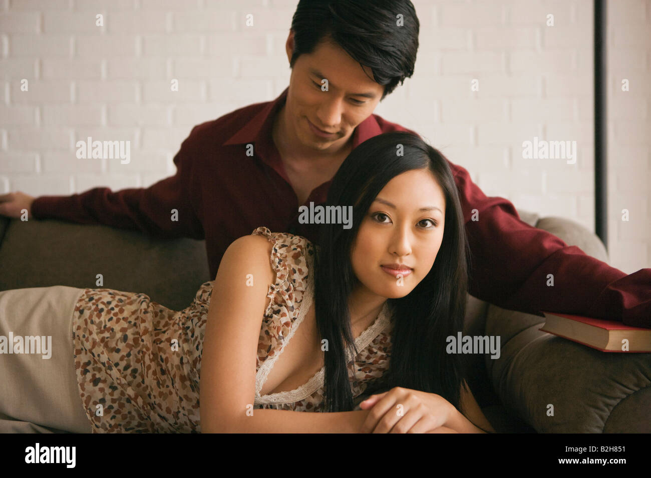 Portrait of a young woman leaning on a young man's laps on a couch ...