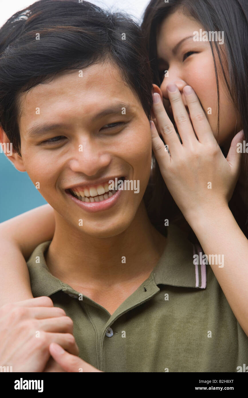 Close-up of a young woman whispering into a young man's ear Stock Photo ...