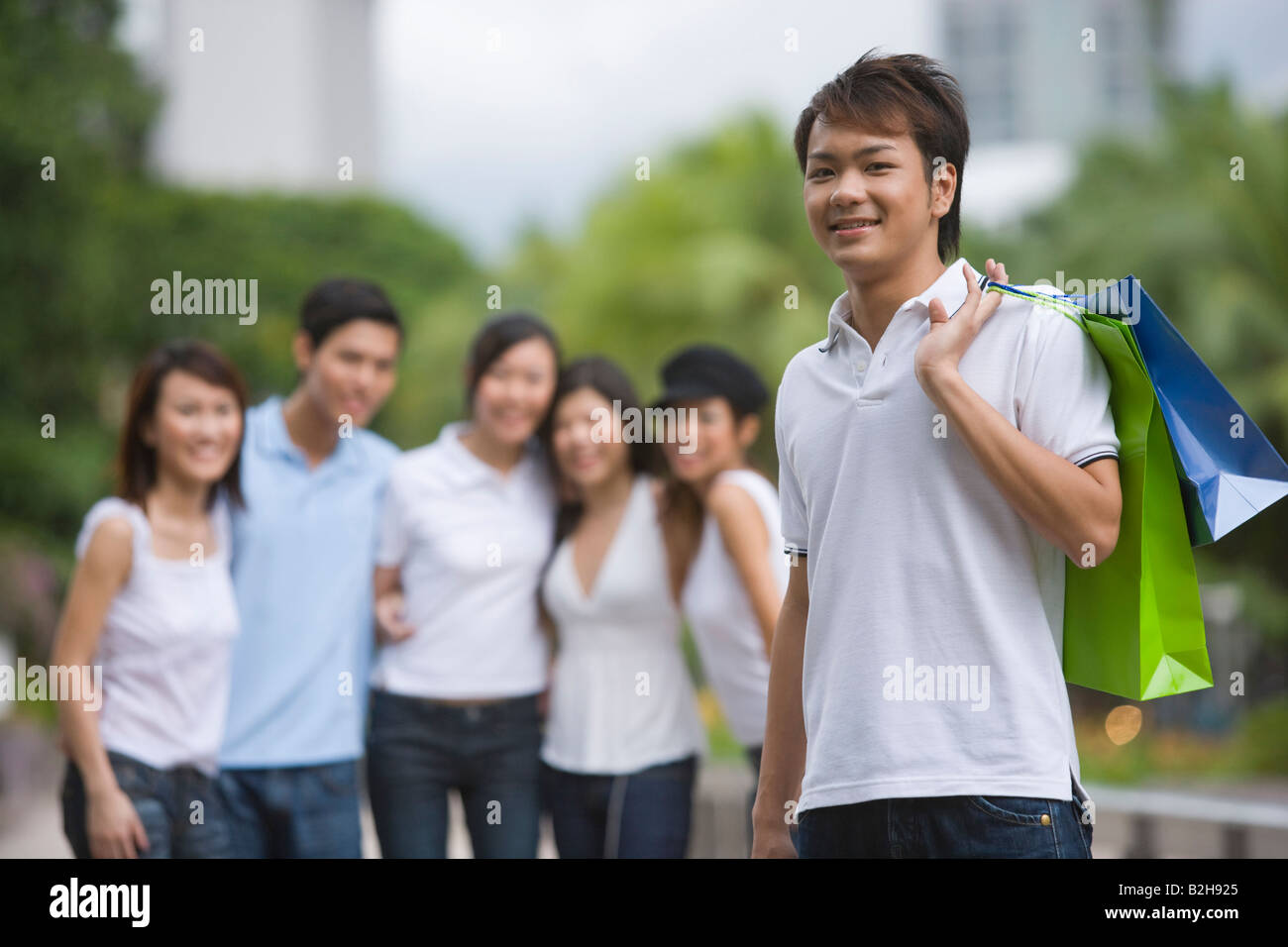 Portrait of a young man smiling with his friends standing in the ...