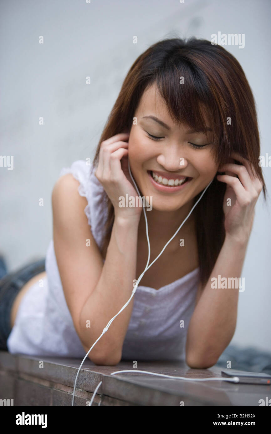 Close-up of a young woman listening to an MP3 player and smiling Stock ...