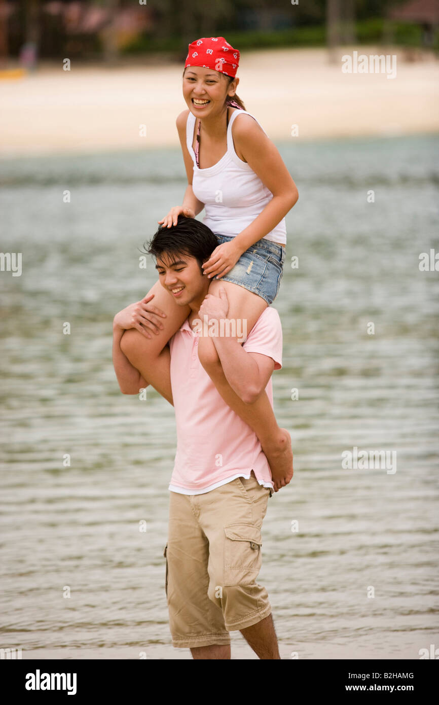 Young woman sitting on a young man's shoulders on the beach Stock Photo ...