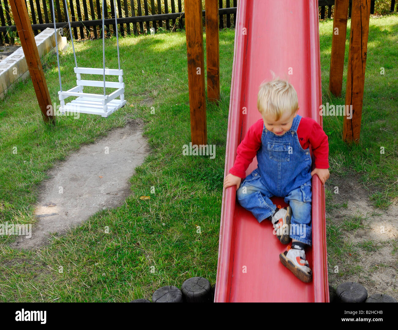 Baby blonde boy sliding down the slide on the playground Stock Photo ...