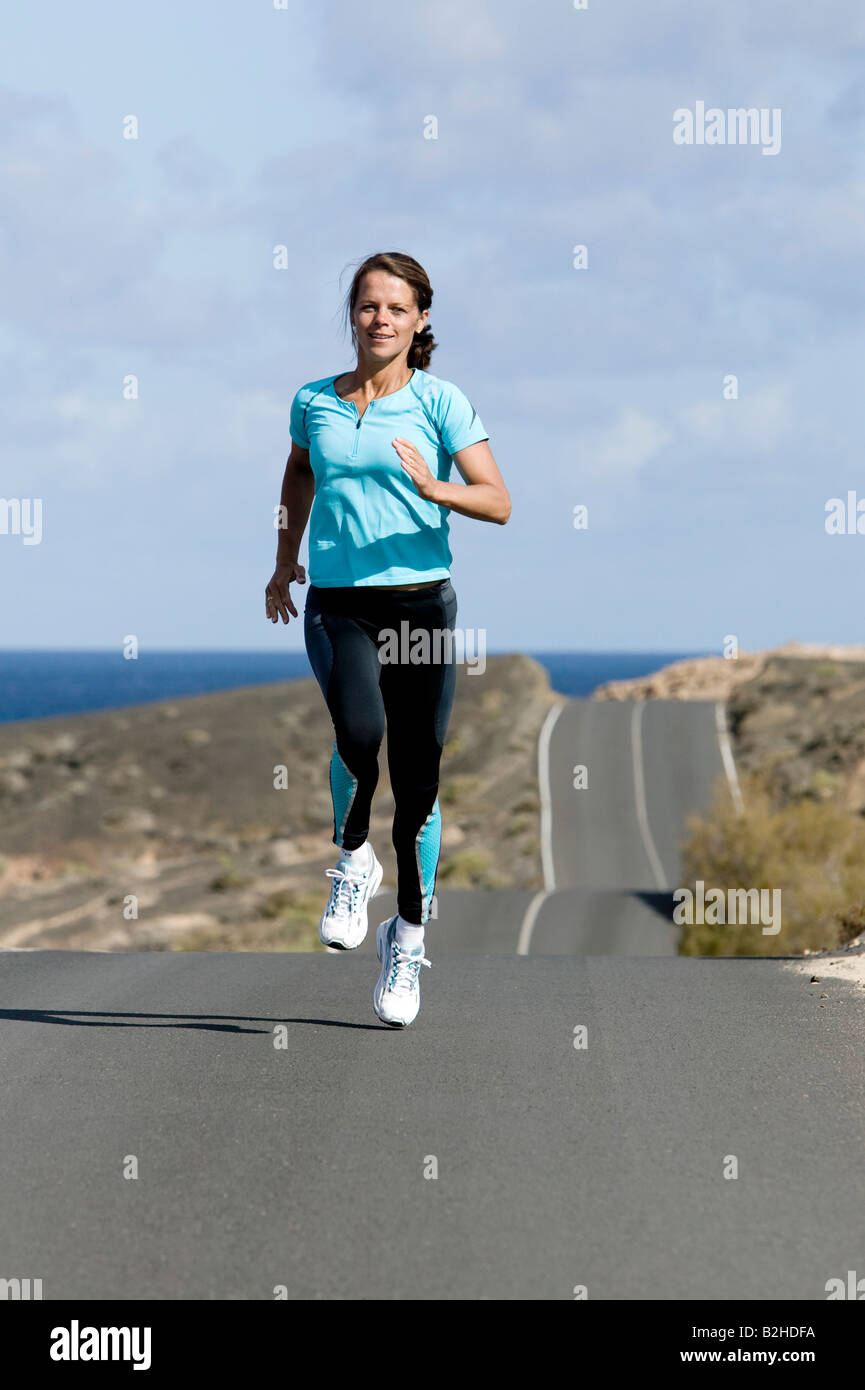 full body portrait of woman jogging along empty road Stock Photo - Alamy