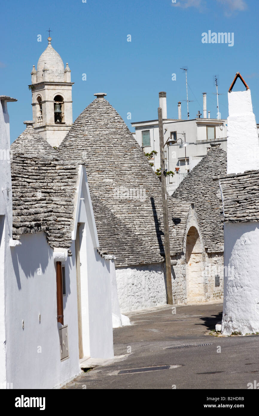 Group of Trulli houses with church tower and modern flats in background ...