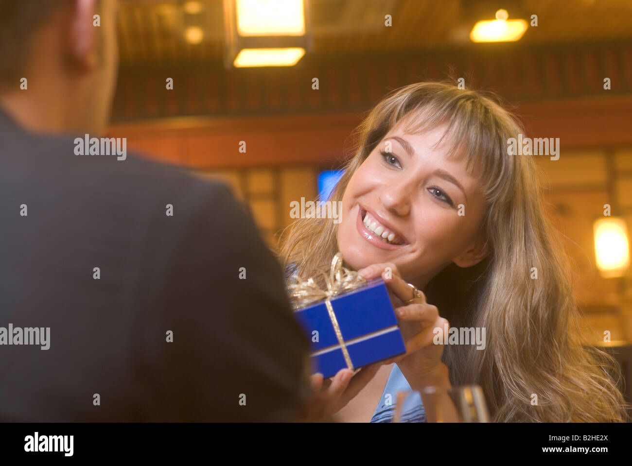 young woman getting present from boyfriend in restaurant Stock Photo ...