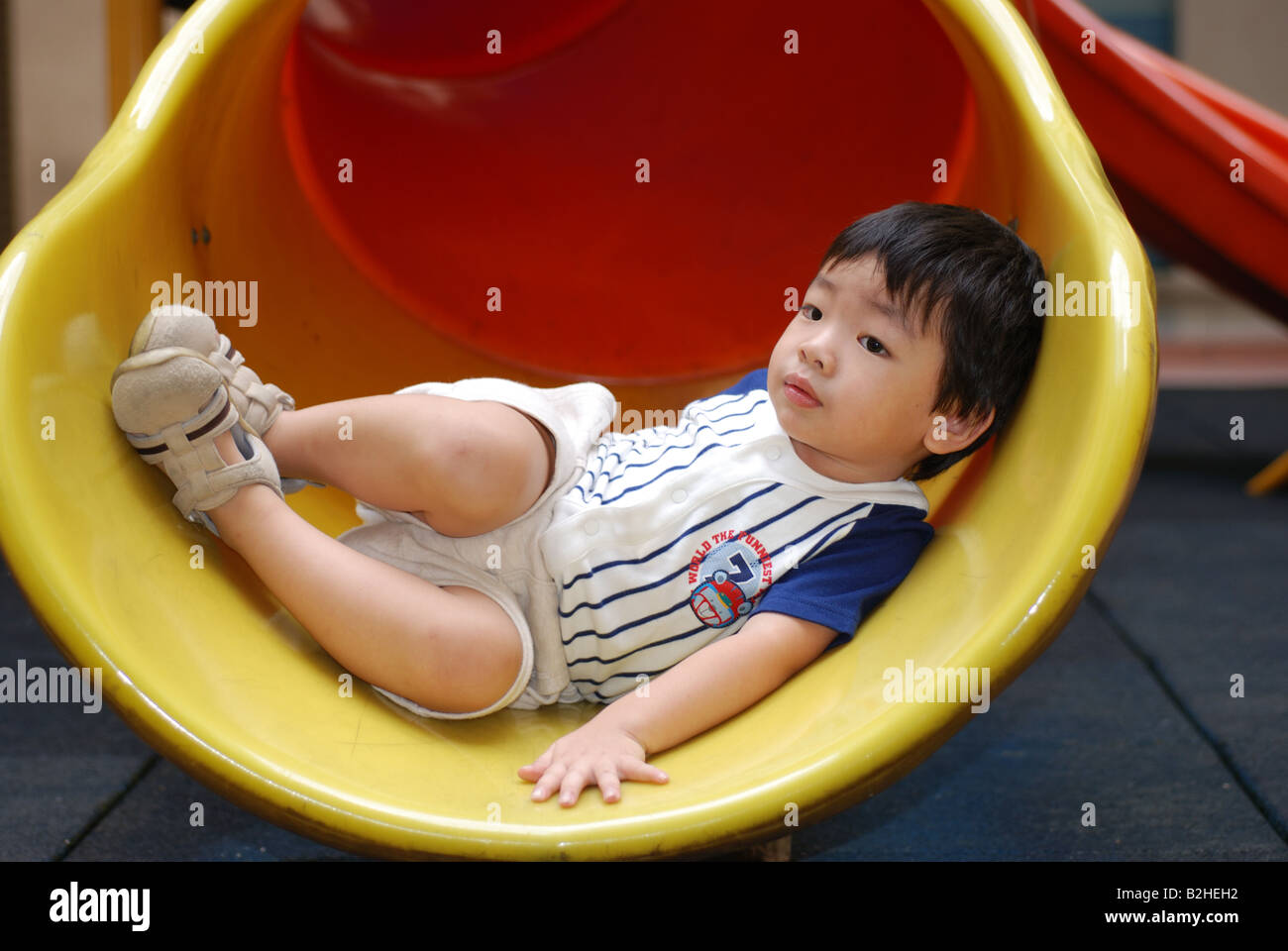 Sad expression of toddler sitting on slide Stock Photo - Alamy
