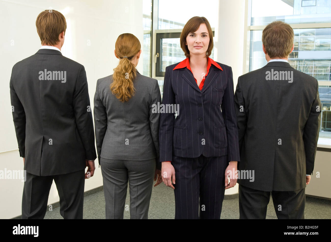 portrait of four business people standing in line one standing with ...
