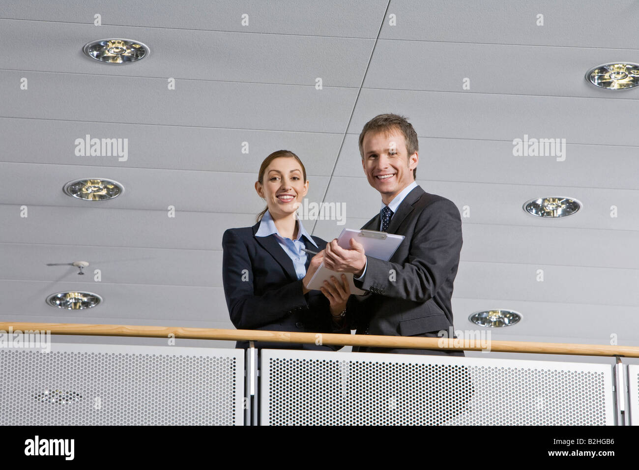 two executives standing at railing in office building Stock Photo - Alamy