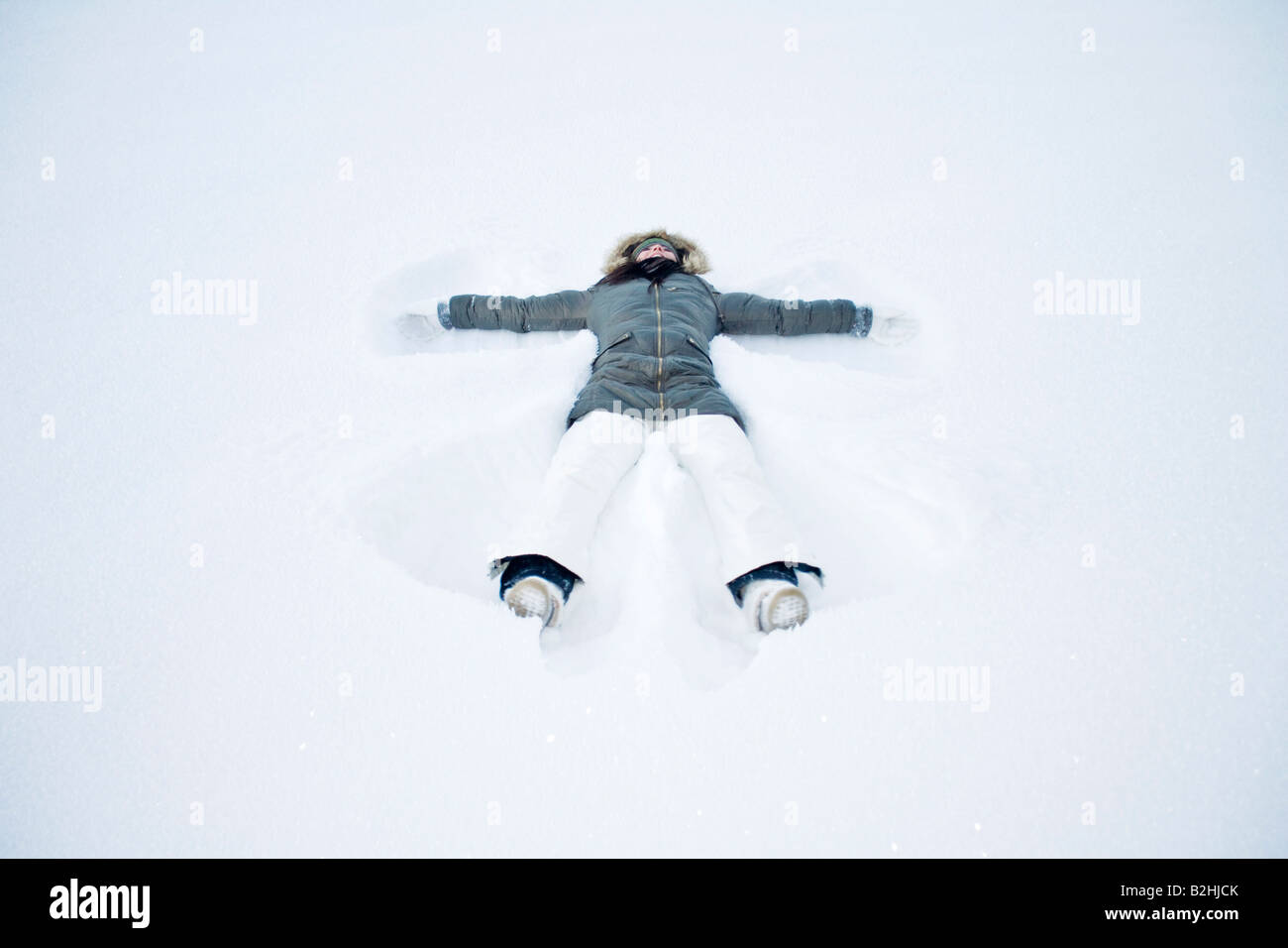 young woman lying in snow doing snow angel Stock Photo - Alamy