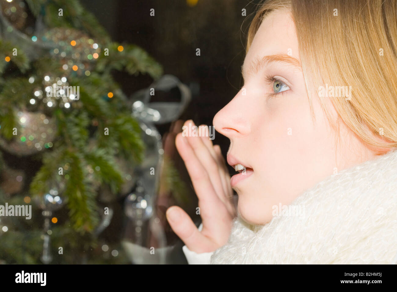 headshot of young woman looking through shop window with christmas ...