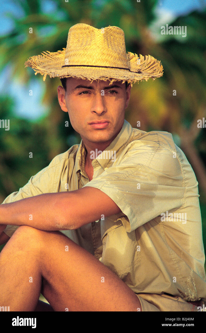Maldives. Side view, close-up of a young man wearing straw hat, sitting ...