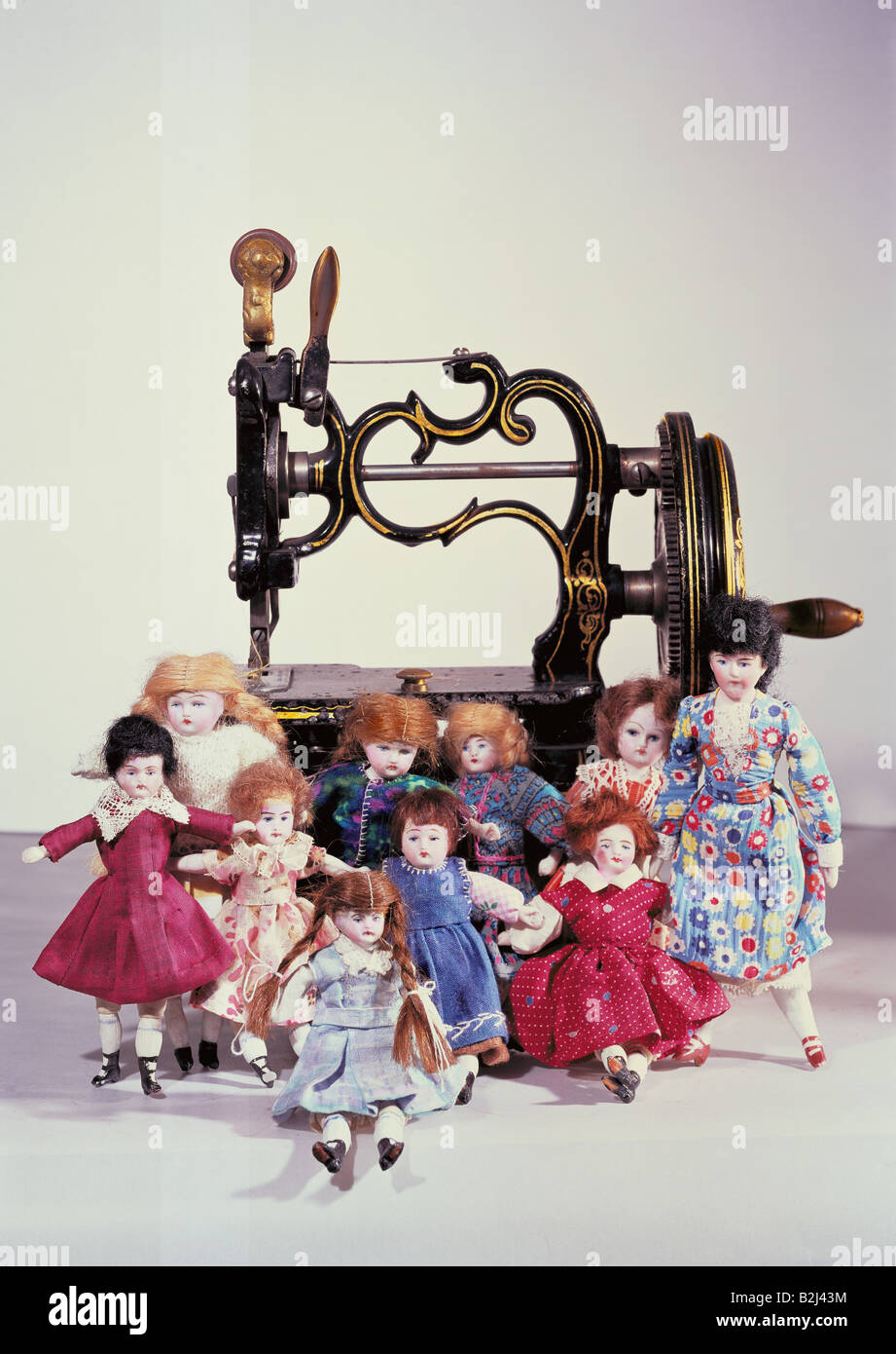 toys, dolls, ten doll childen in fronmt of a child sewing machine ...