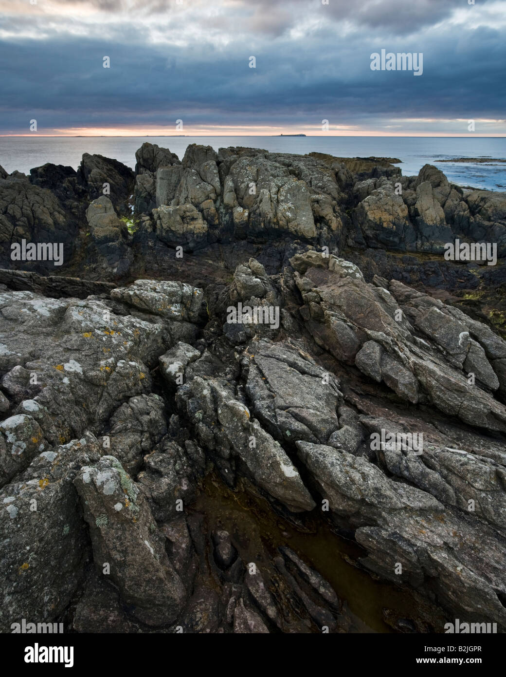 Rocks on the coast at Bamburgh looking toward Inner Farne ...