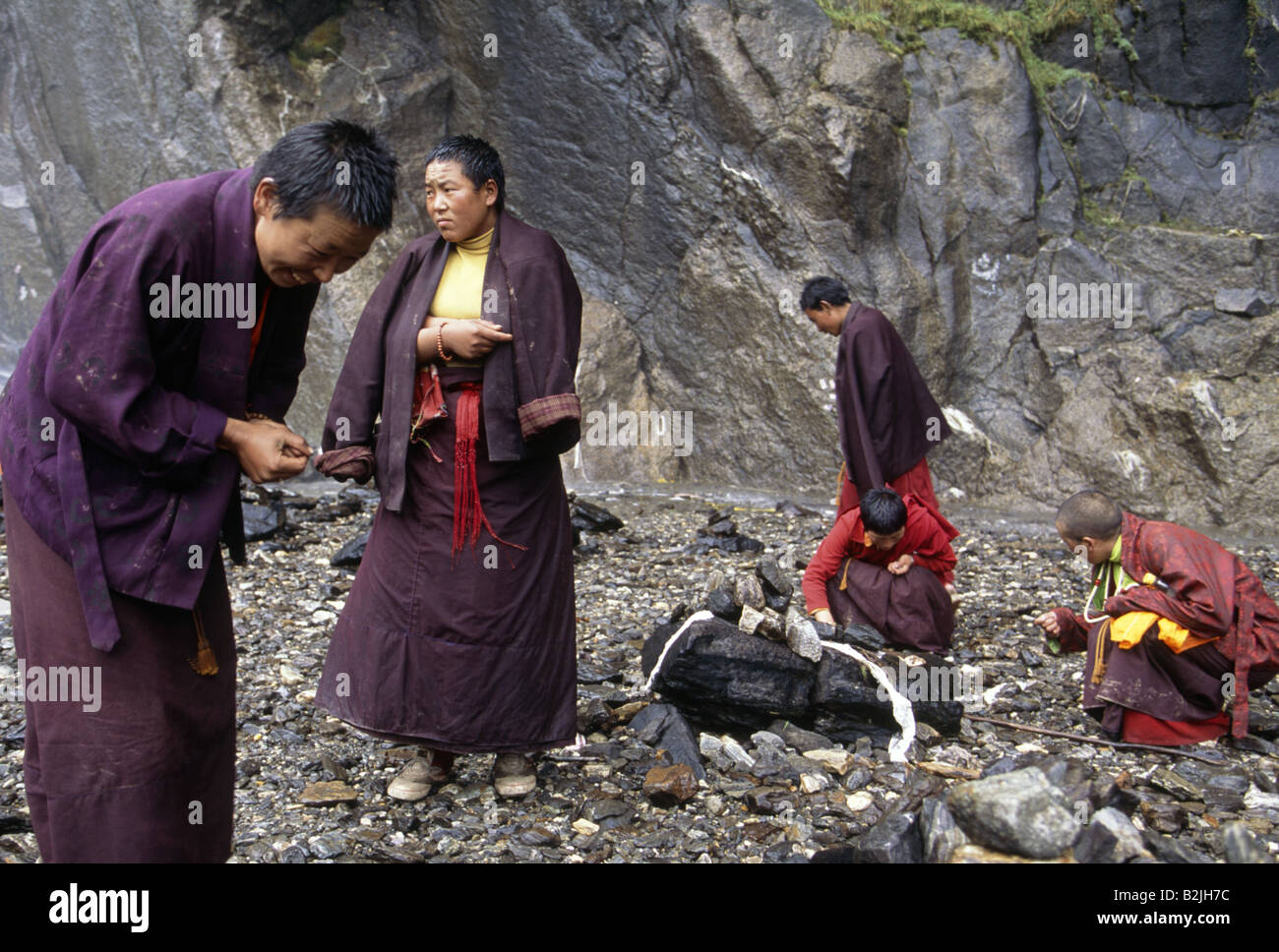 Sacred waterfall Tibetan Buddhist nuns women in robes collecting rocks ...
