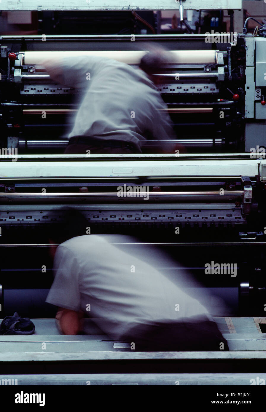 Two pressman in a blur of action while working on a commercial offset ...
