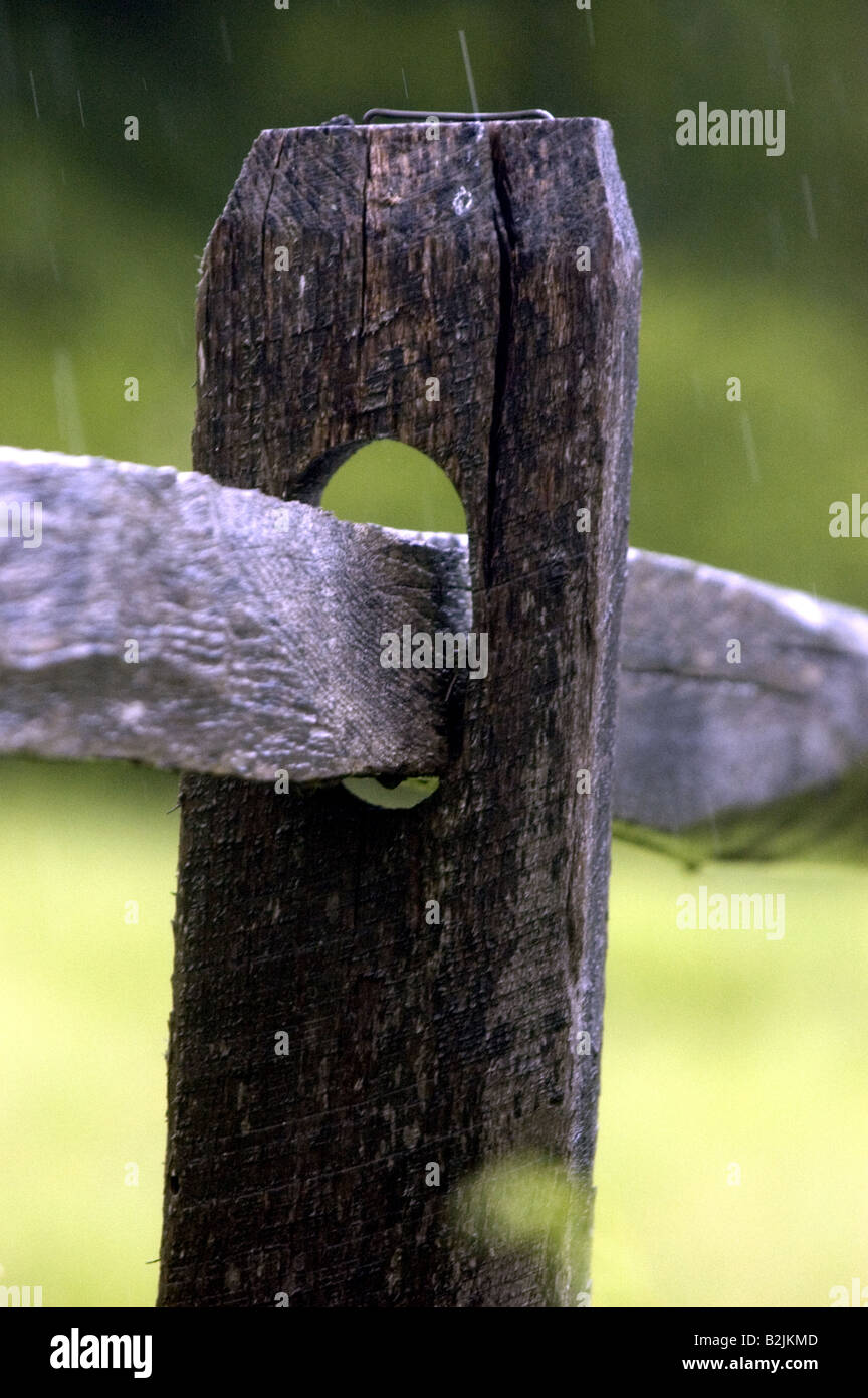 A fence goes through a wooden fence post at a farm protecting livestock ...