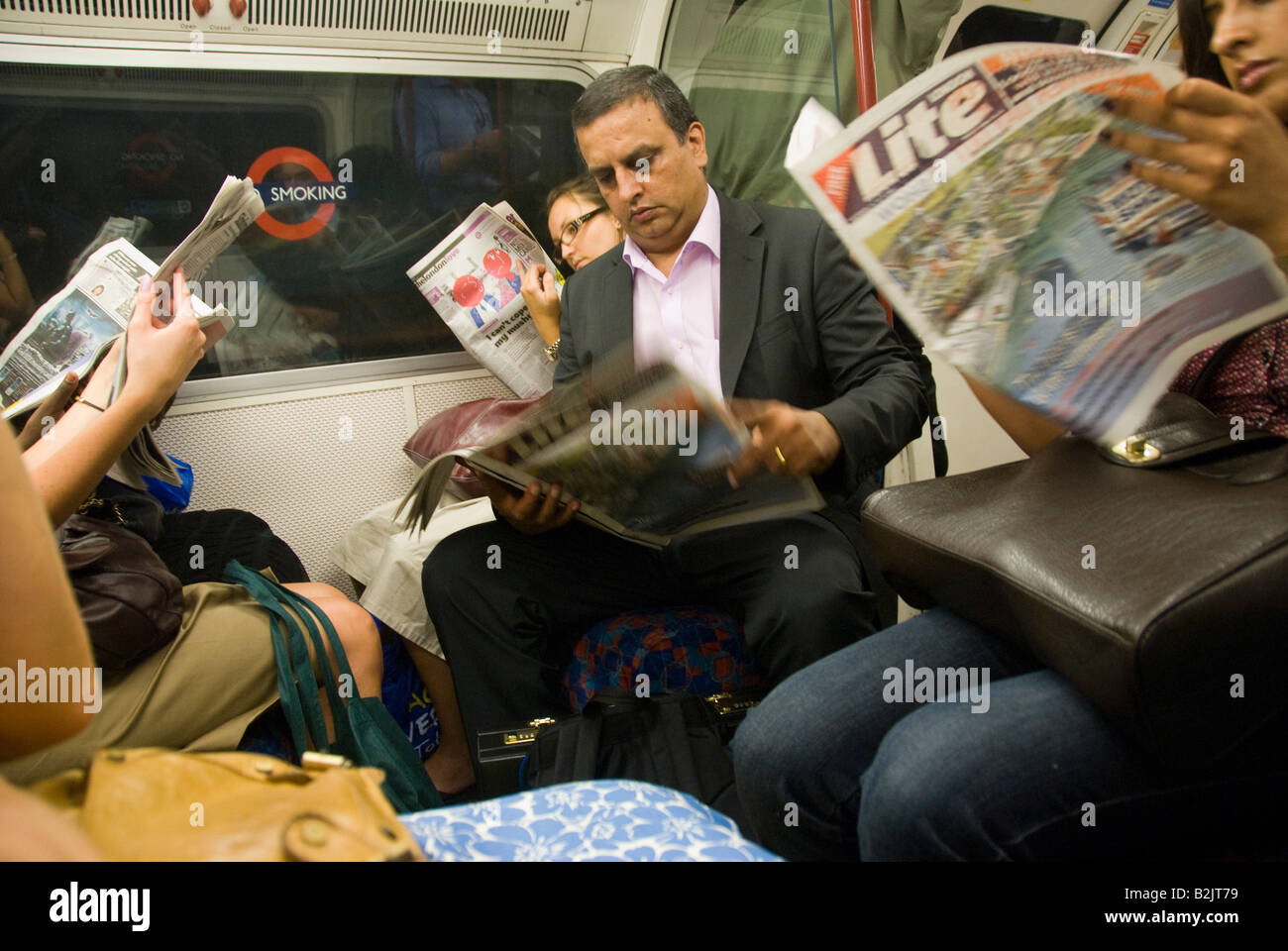 People on a tube train reading free newspaper London Lite i Stock Photo ...