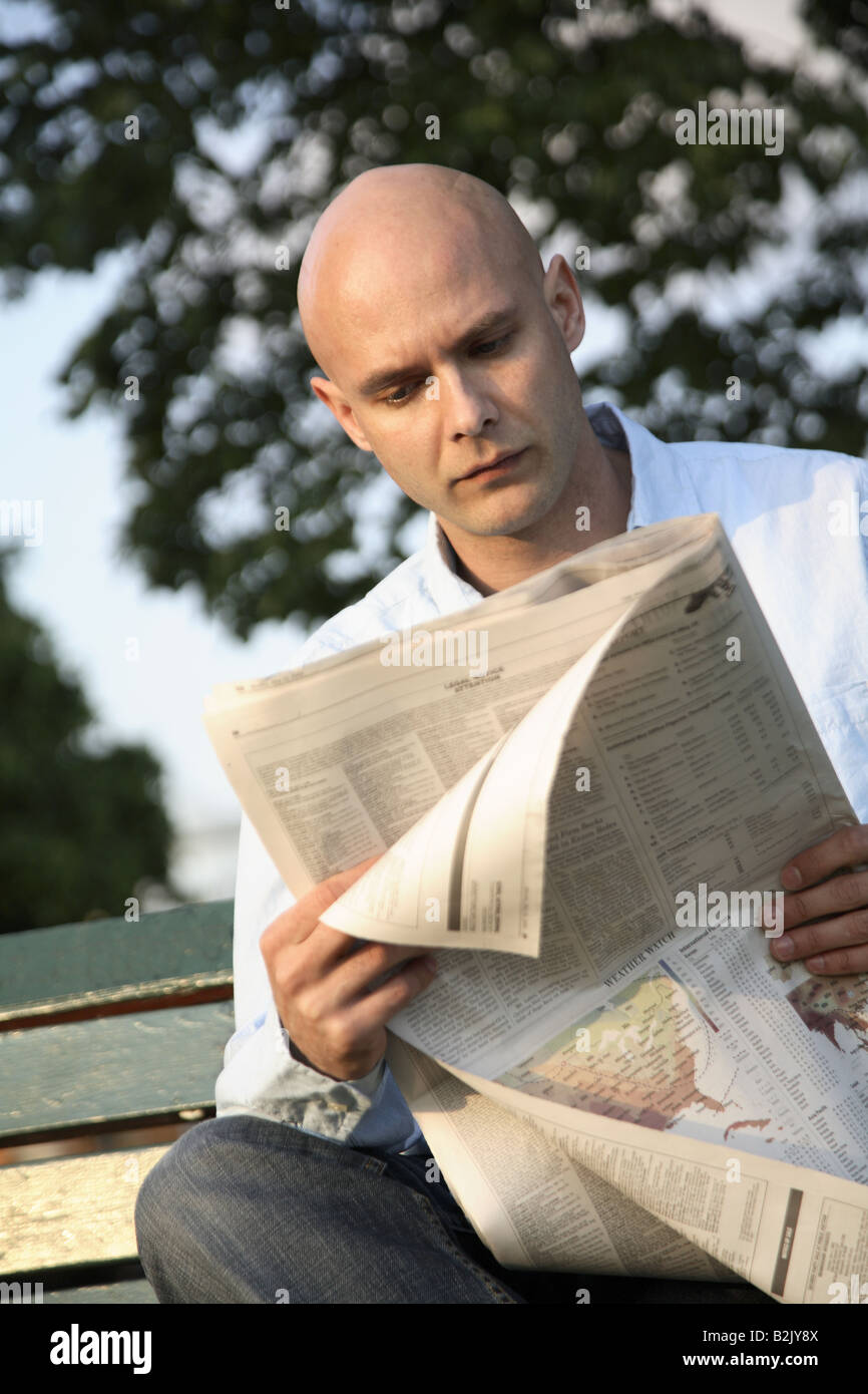 man on park bench reading newspaper Stock Photo - Alamy