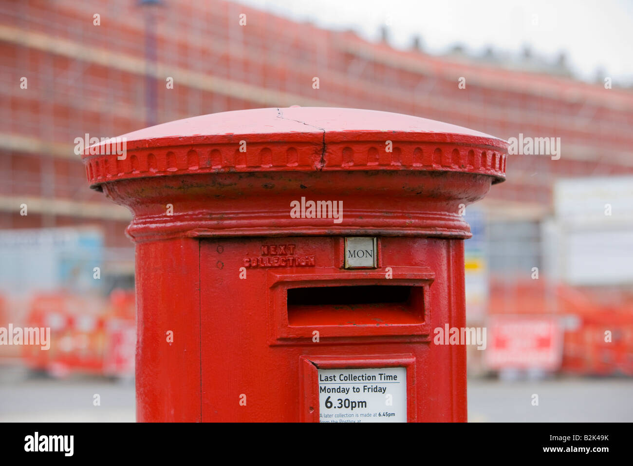 Postbox with scaffolded building in the background Stock Photo - Alamy