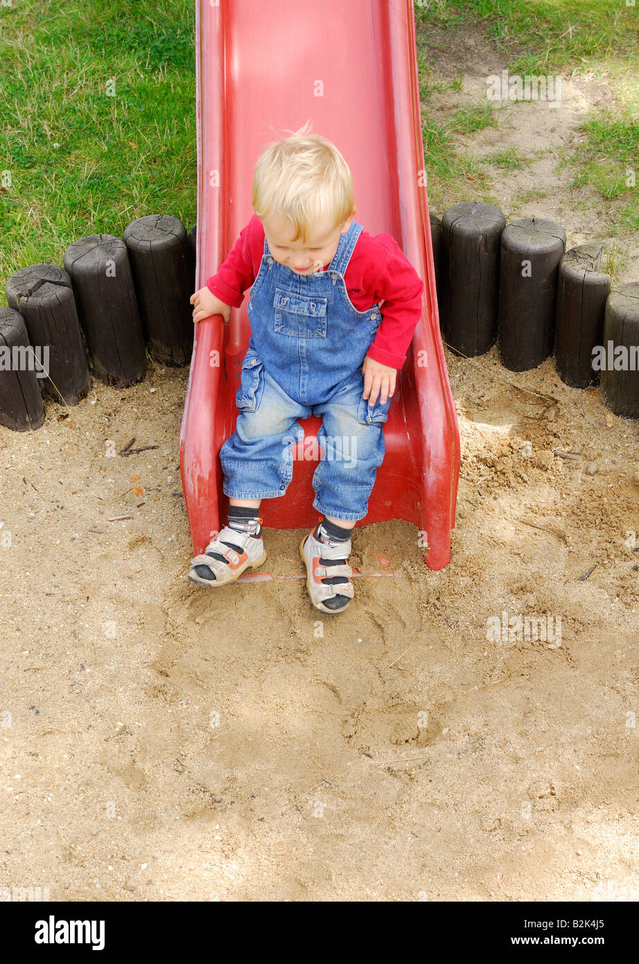 Baby blonde boy sliding down the slide on the playground Stock Photo ...