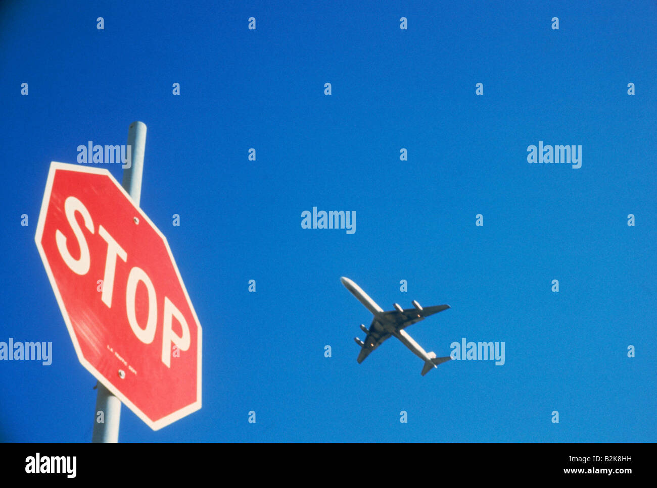 Passenger jet flying over stop sign Stock Photo - Alamy