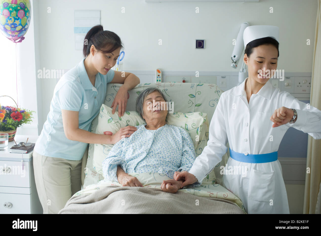Female nurse checking pulse of a patient and smiling Stock Photo - Alamy