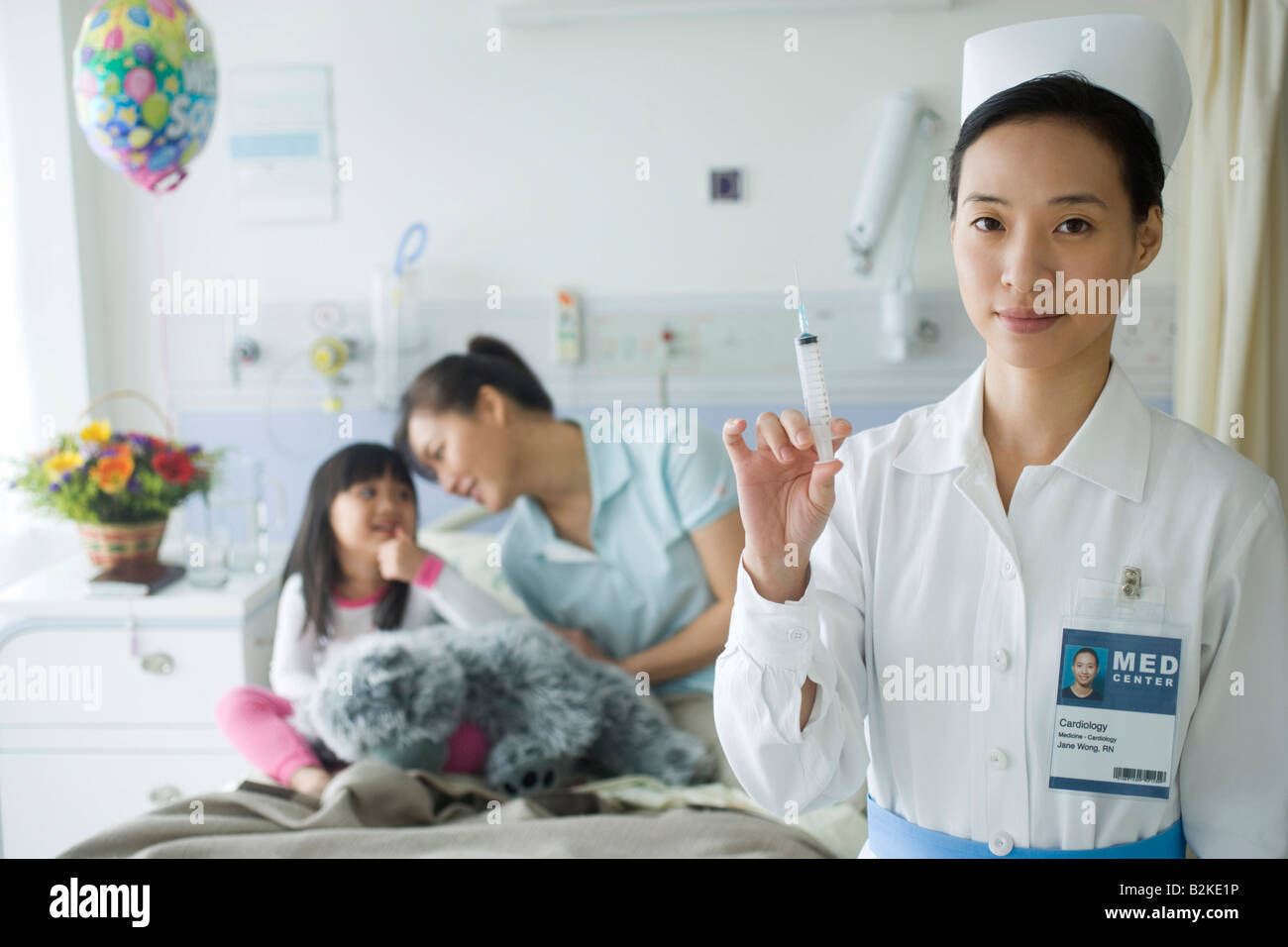 Portrait of a female nurse holding a syringe with two people sitting ...