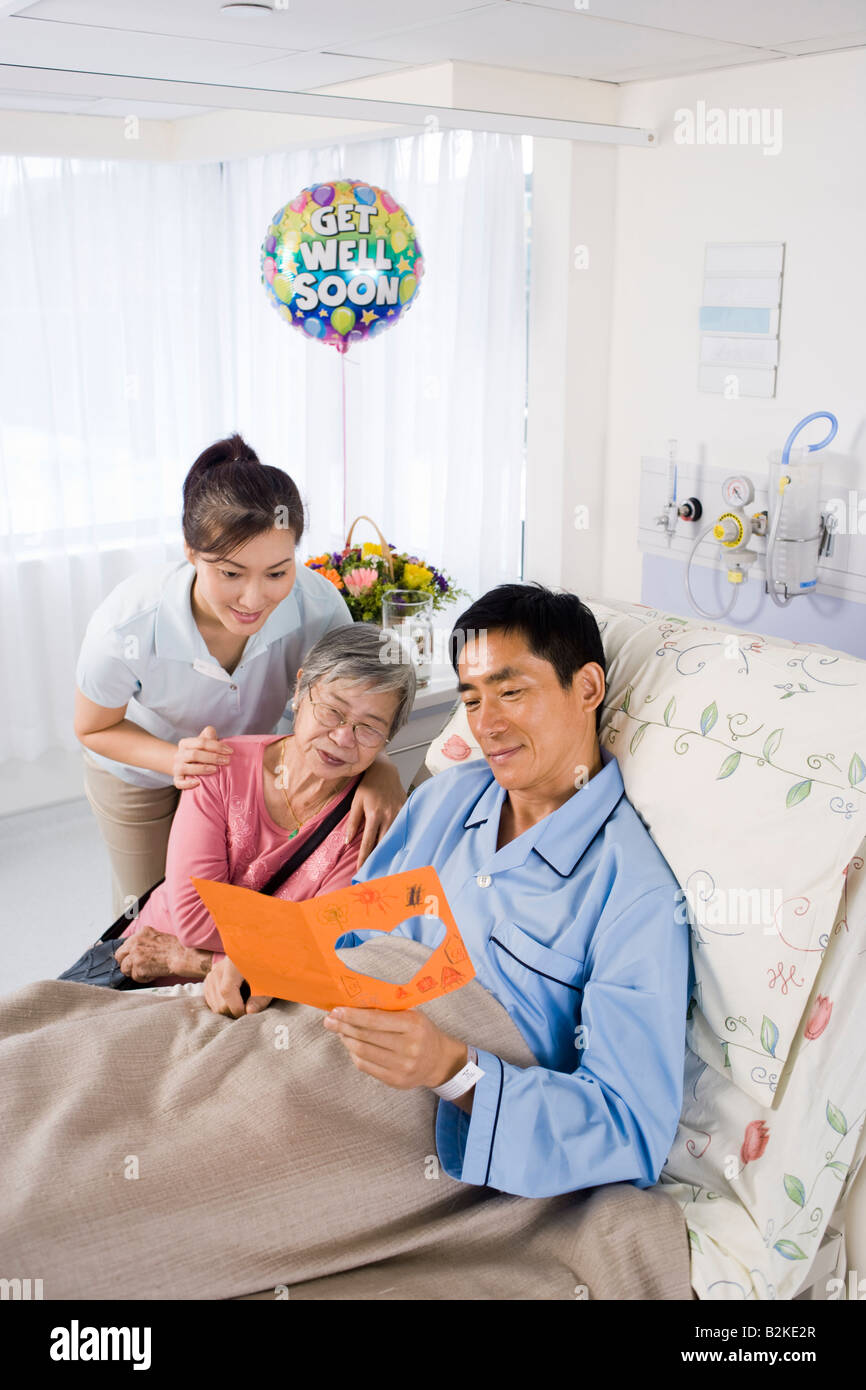 Patient reading a Get Well card with his family beside him Stock Photo ...