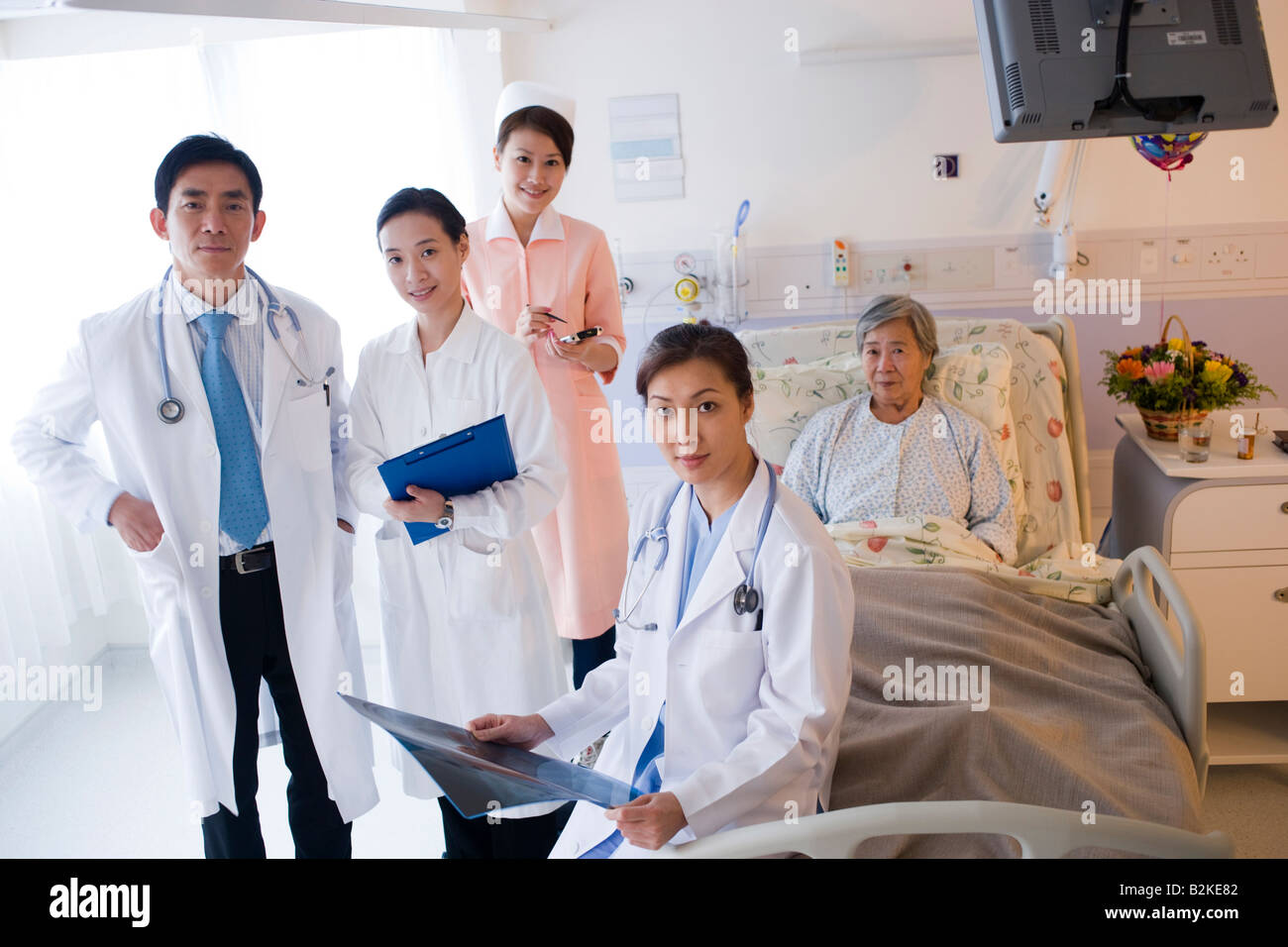 Two doctors with a patient and two female nurses in a hospital room ...