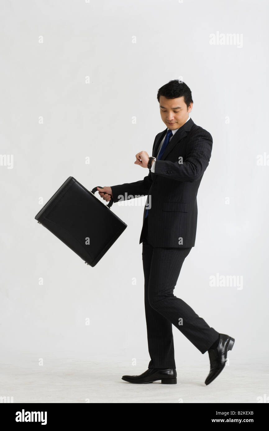 Side profile of a businessman carrying a briefcase and checking the ...