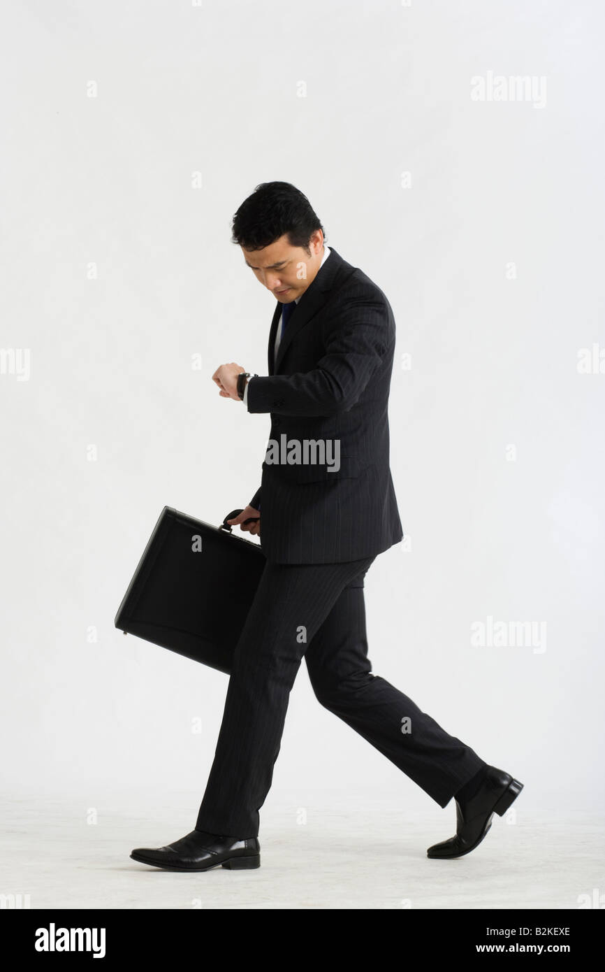 Side profile of a businessman carrying a briefcase and checking the ...