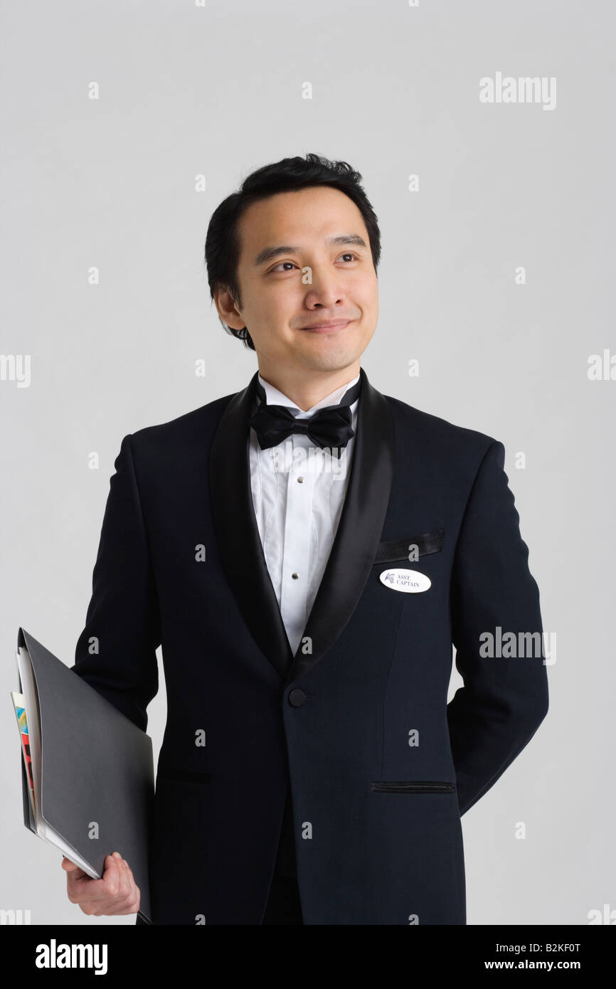 Close-up of a waiter holding a menu and thinking Stock Photo - Alamy