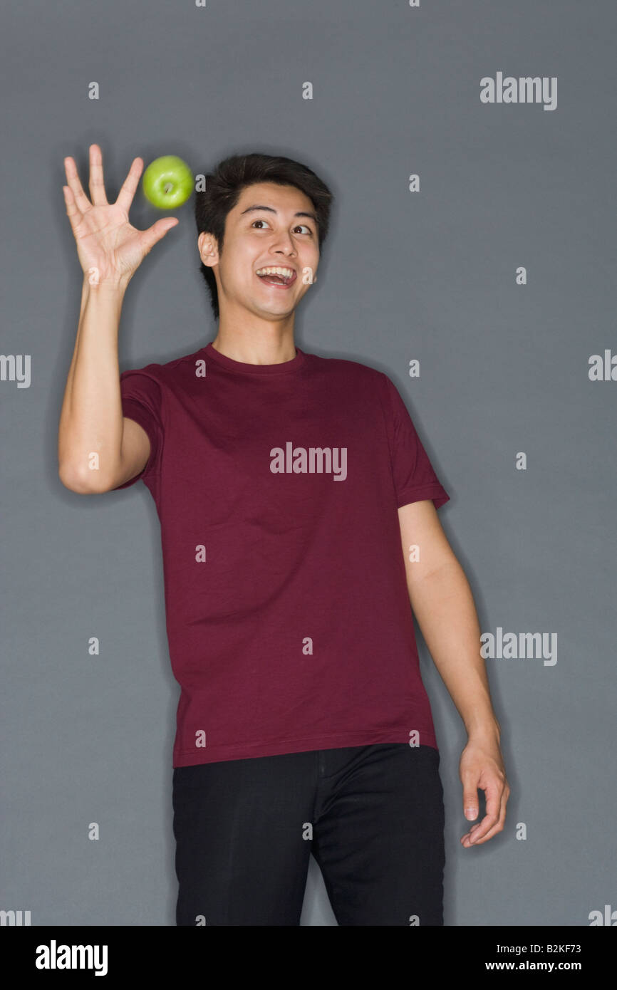 Young man tossing an apple and smiling Stock Photo - Alamy