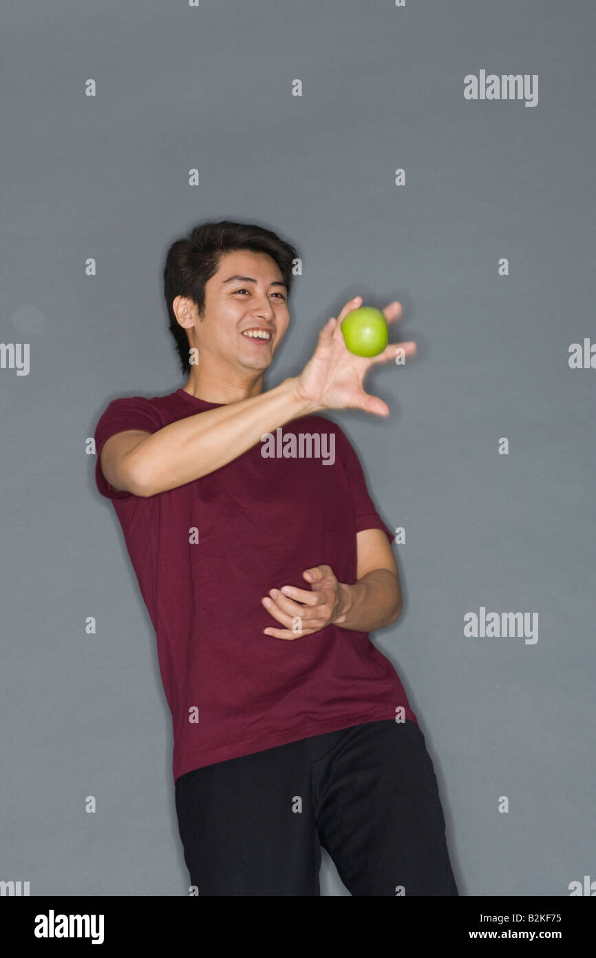 Young man tossing an apple and smiling Stock Photo - Alamy