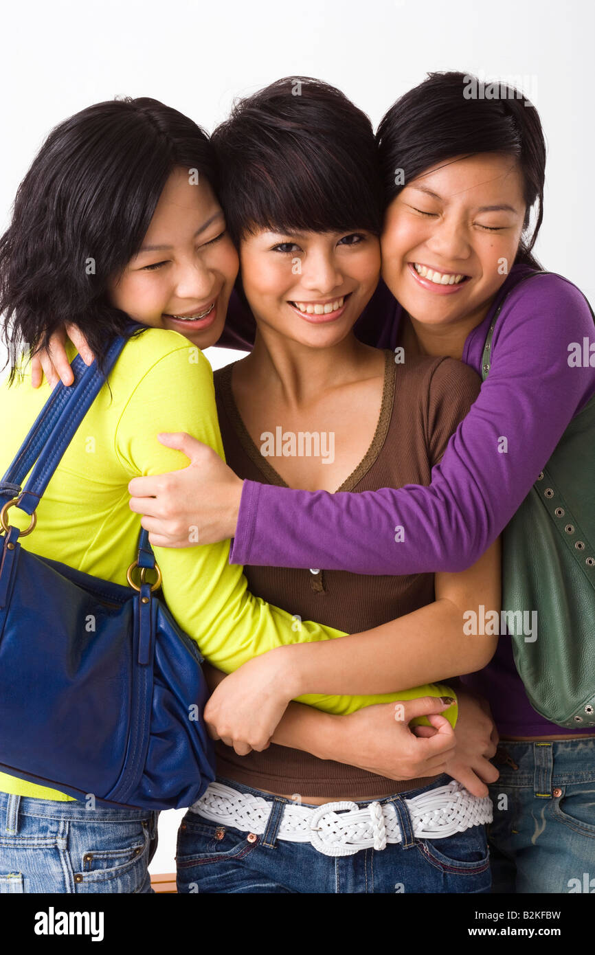 Three young women hugging each other and smiling Stock Photo - Alamy