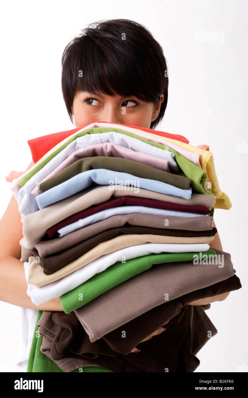 Close-up of a young woman holding a stack of clothes Stock Photo - Alamy