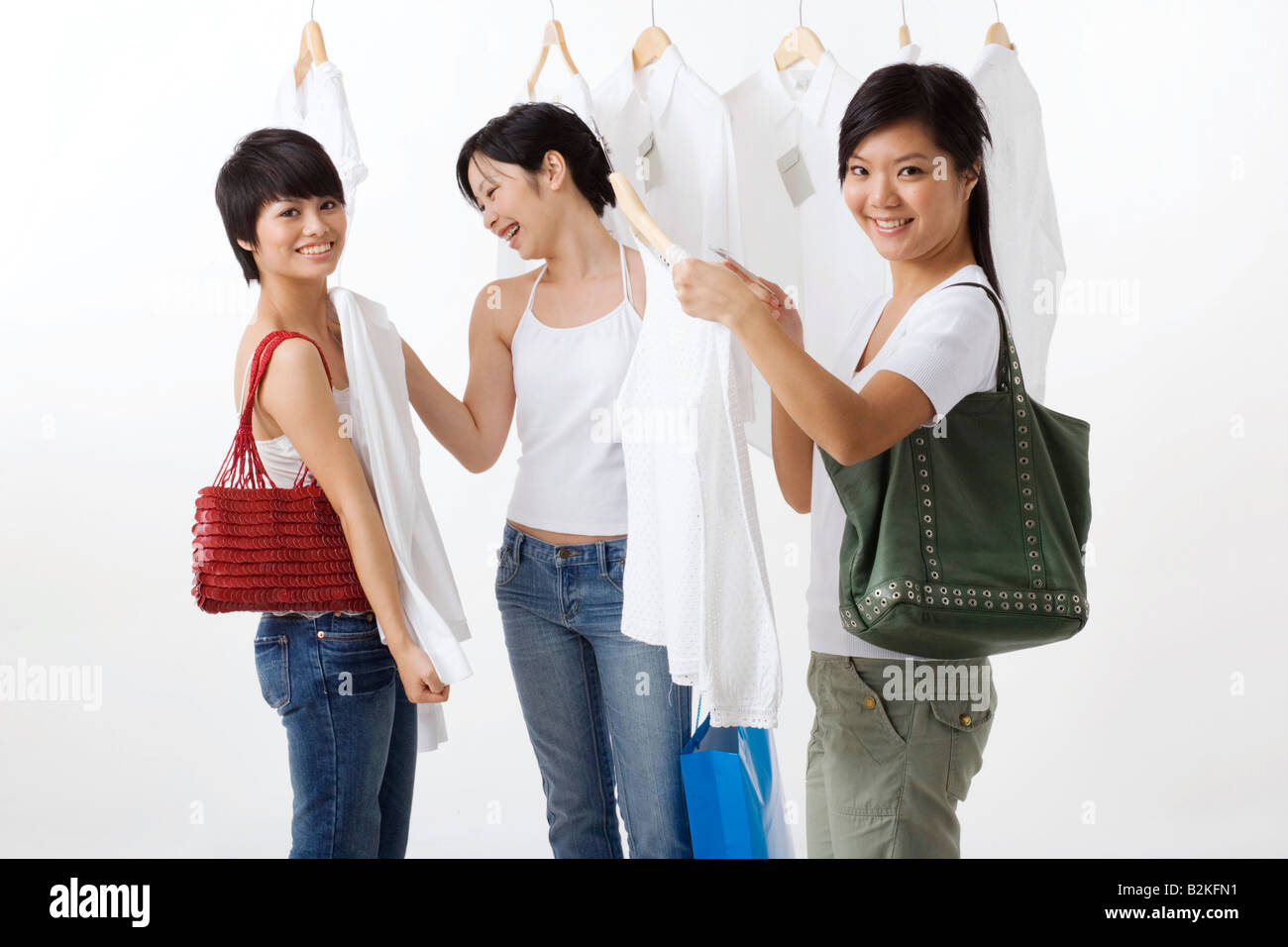 Three young women selecting dresses in a clothing store Stock Photo - Alamy