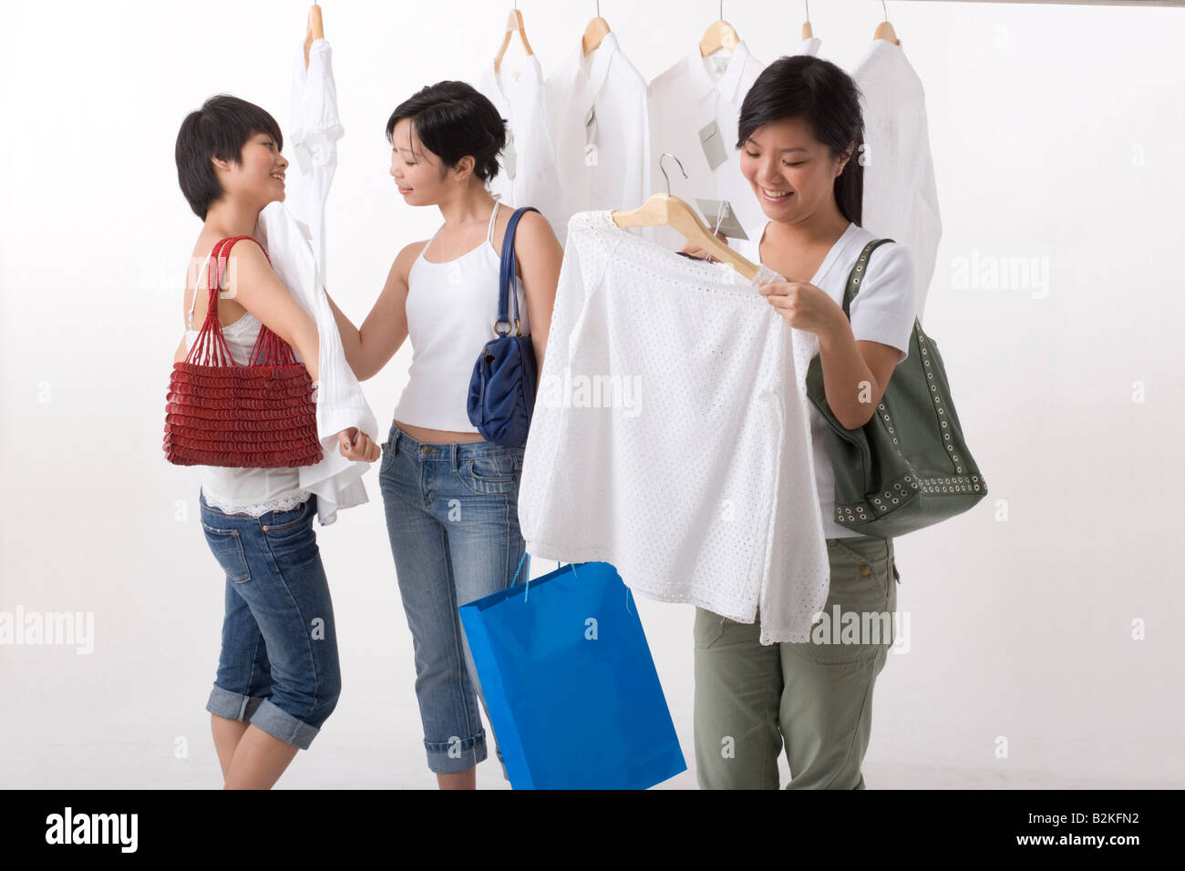 Three young women selecting dresses in a clothing store Stock Photo - Alamy