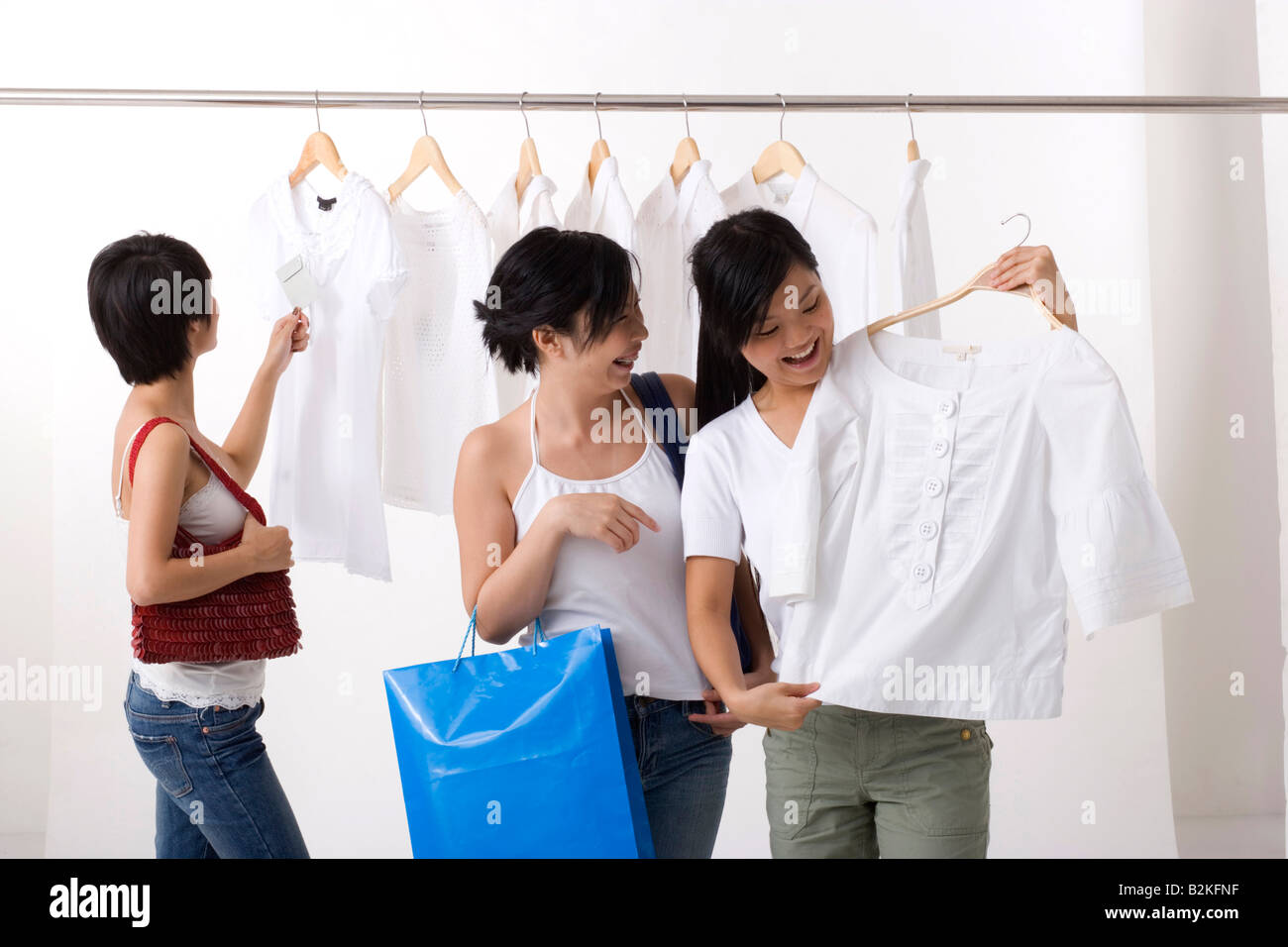 Three young women selecting dresses in a clothing store Stock Photo - Alamy