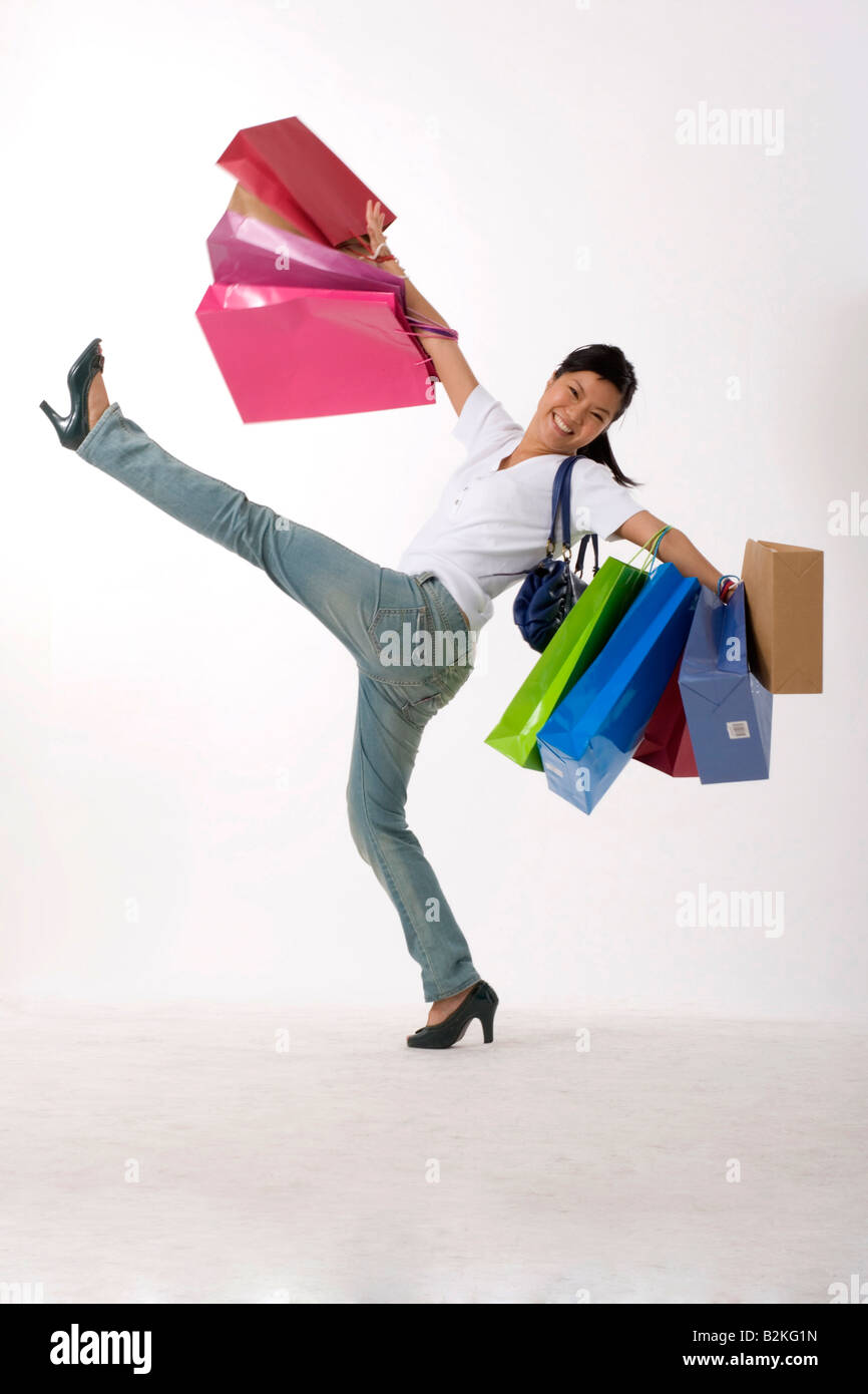 Young woman carrying shopping bags and dancing Stock Photo - Alamy