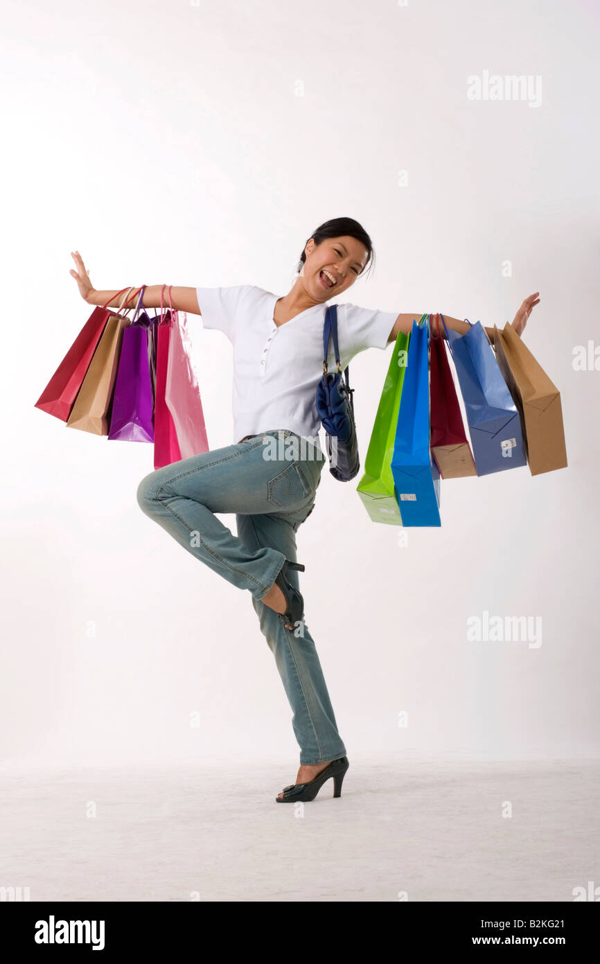 Young woman carrying shopping bags and dancing Stock Photo - Alamy