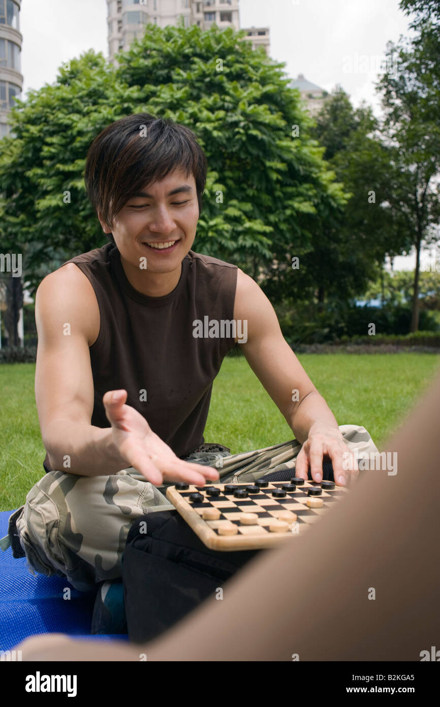 Young man playing chess in a park and smiling Stock Photo - Alamy