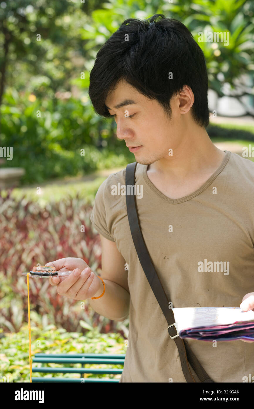 Close-up of a young man holding a compass and a map Stock Photo - Alamy