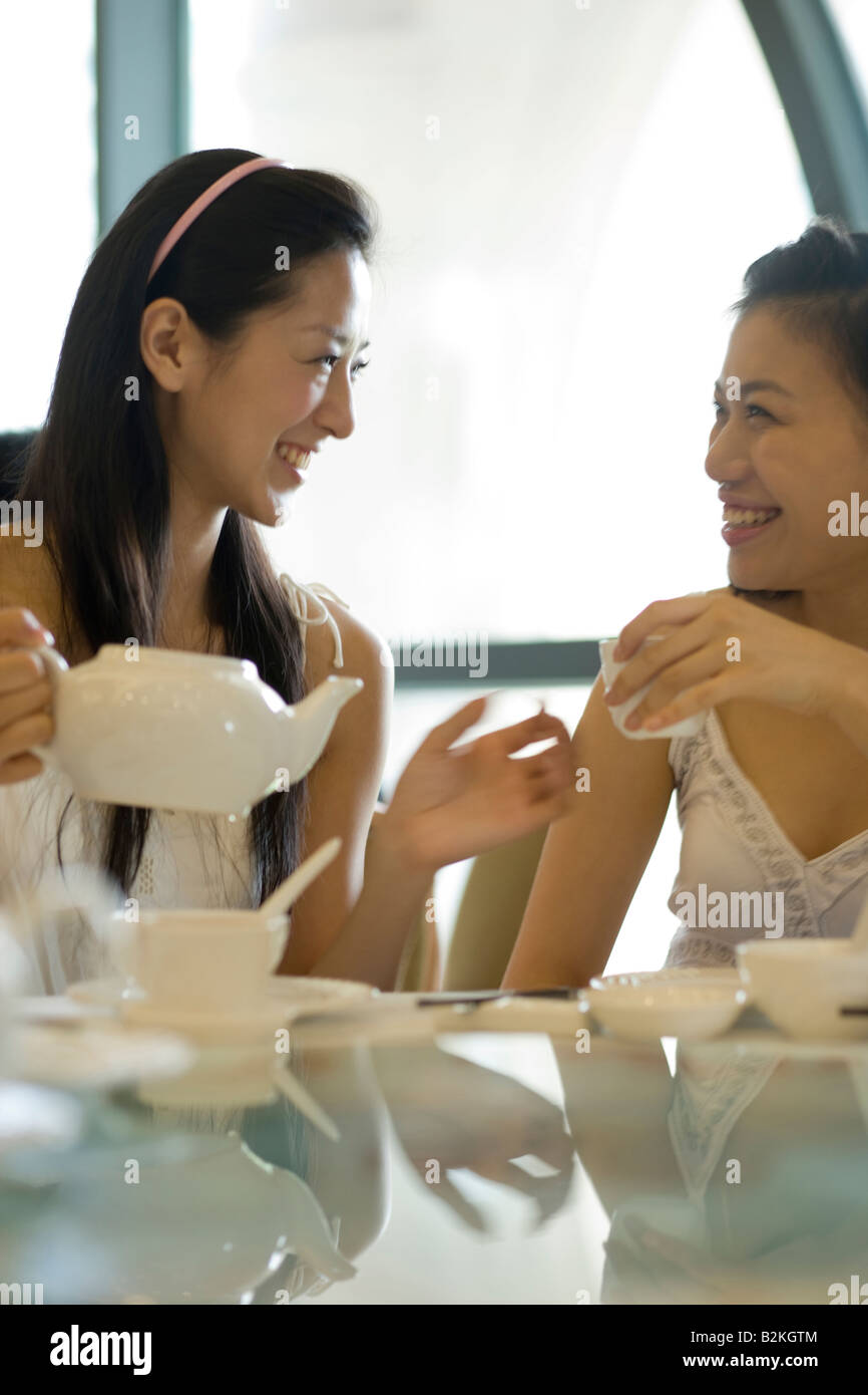 Two young women having tea in a restaurant and smiling Stock Photo - Alamy